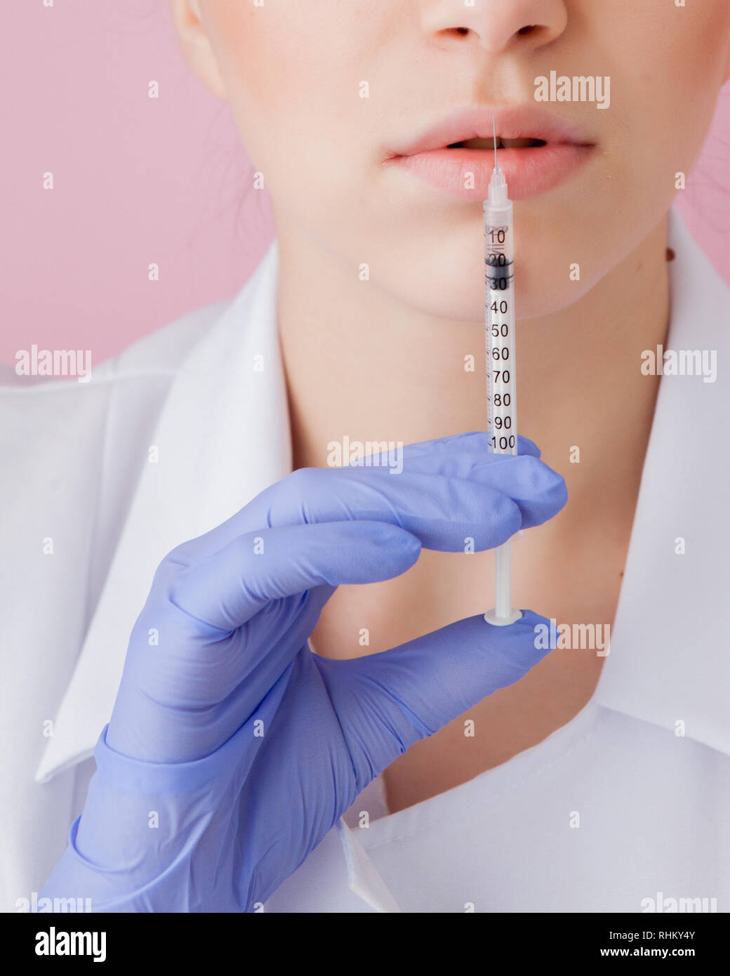 Close up nurse holding a syringe for injection, on pink background ...