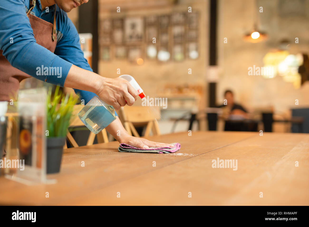 Waiter cleaning the table with spray disinfectant on table in ...