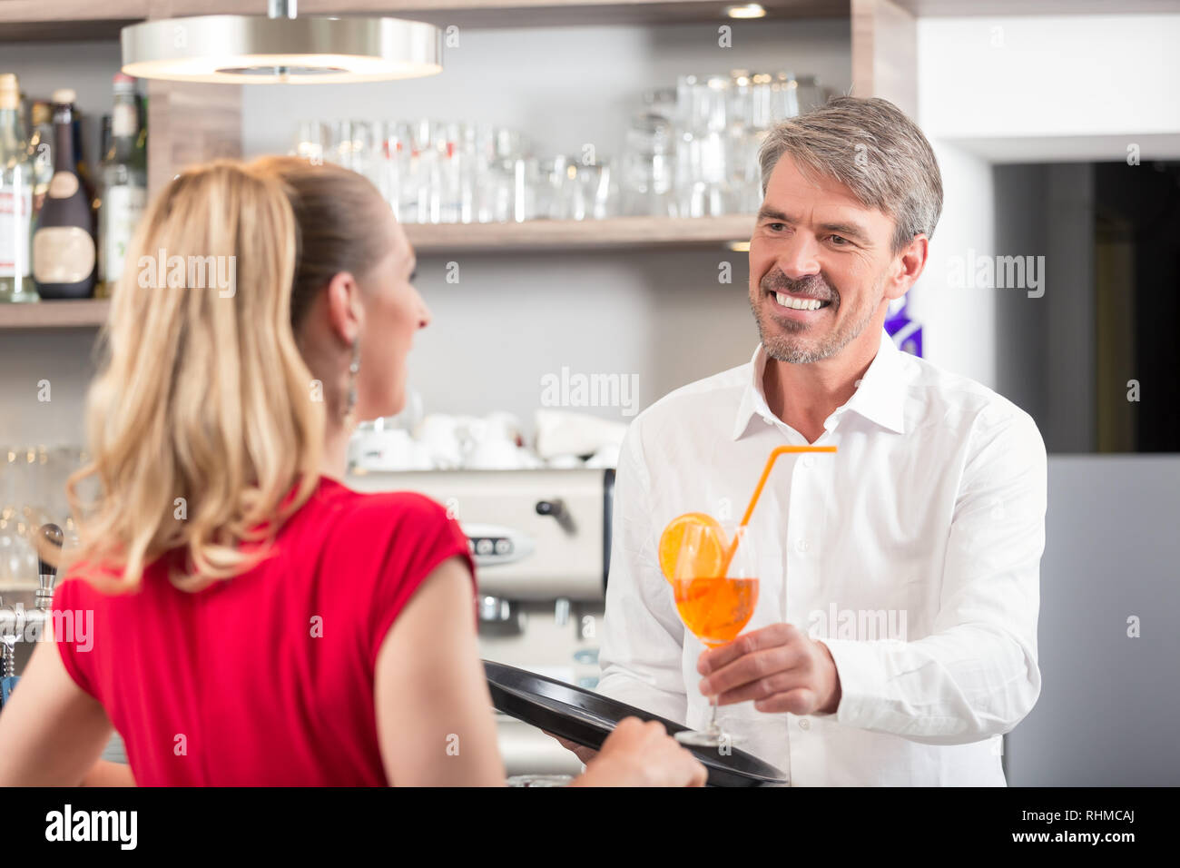 Male waiter serving cocktail to woman Stock Photo - Alamy