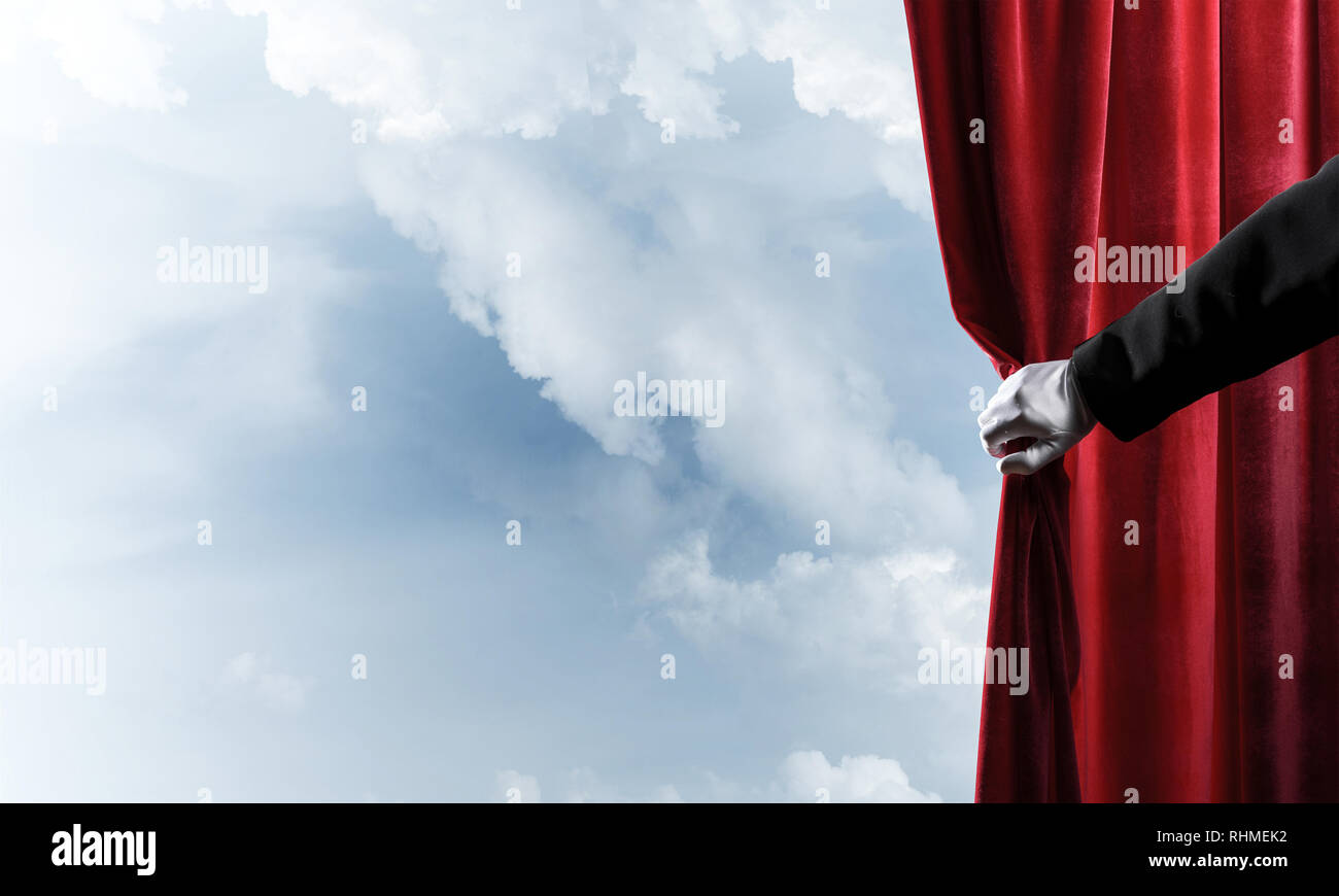 Cloudy landscape behind red curtain and hand holding it Stock Photo - Alamy