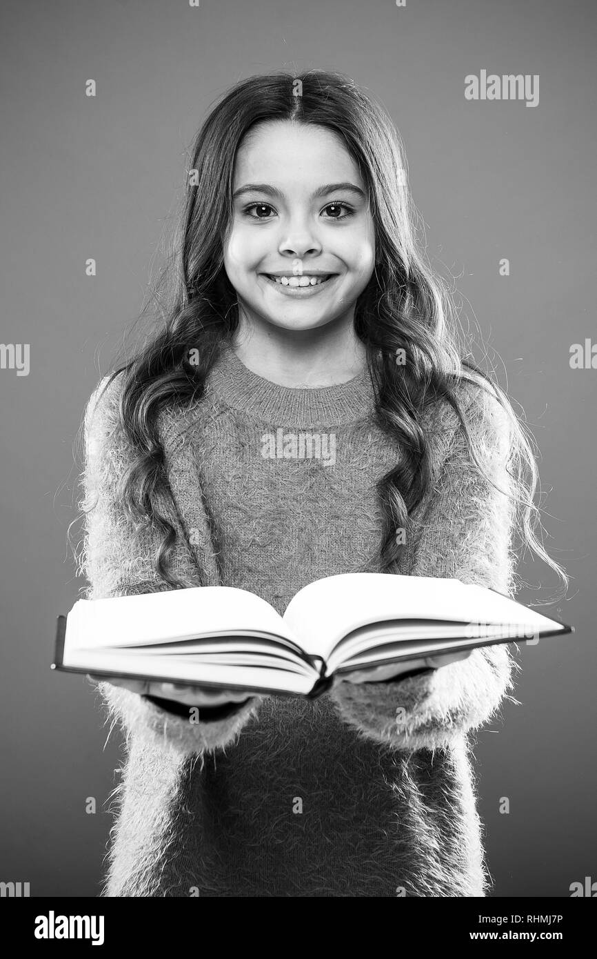 Girl hold book read story over orange background. Child enjoy reading ...