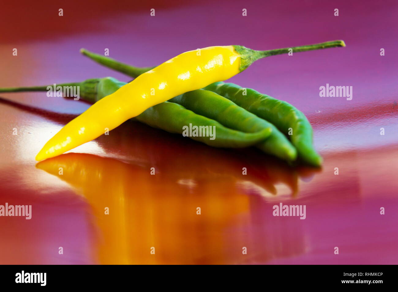 Fresh yellow and green hot chilli peppers on red background, studio ...