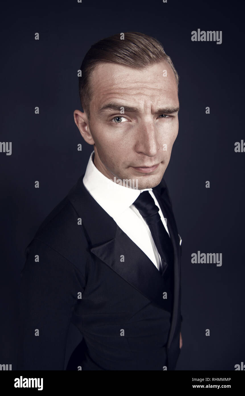 Businessman in black suit wink eye on dark background. Flirt, intent ...