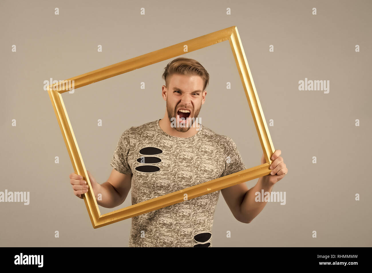 Man shout with picture frame on grey background. Angry macho with beard ...