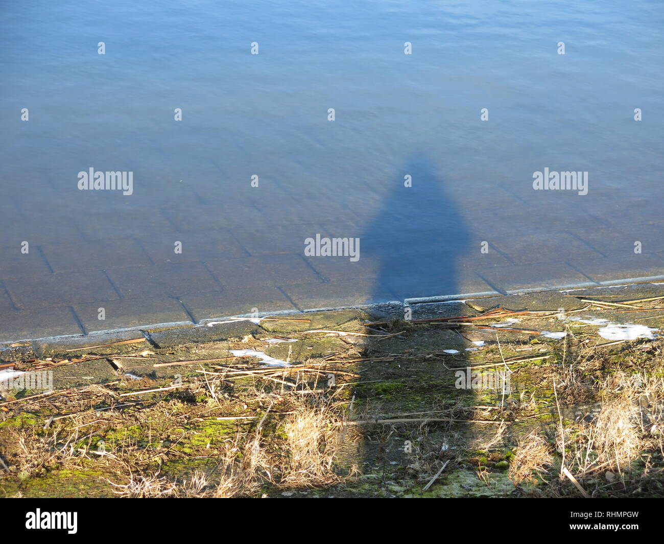 The low winter sun casts a long shadow of a female outline standing at ...