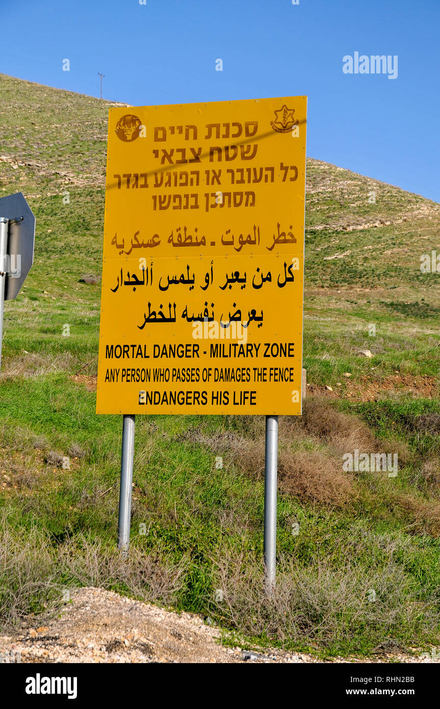 Israel, Golan Heights. The Syrian Israeli border fence a yellow warning ...