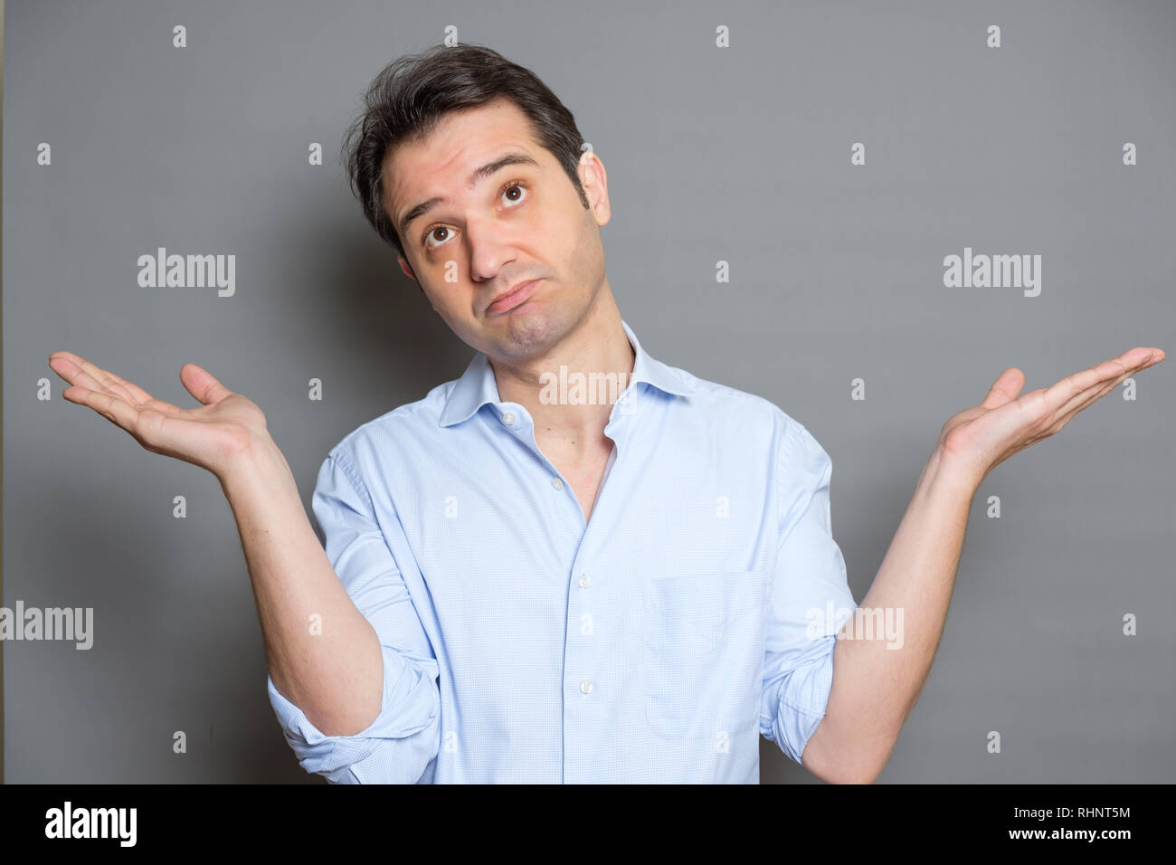 Confused man wearing shirt standing and shrugging over grey background ...