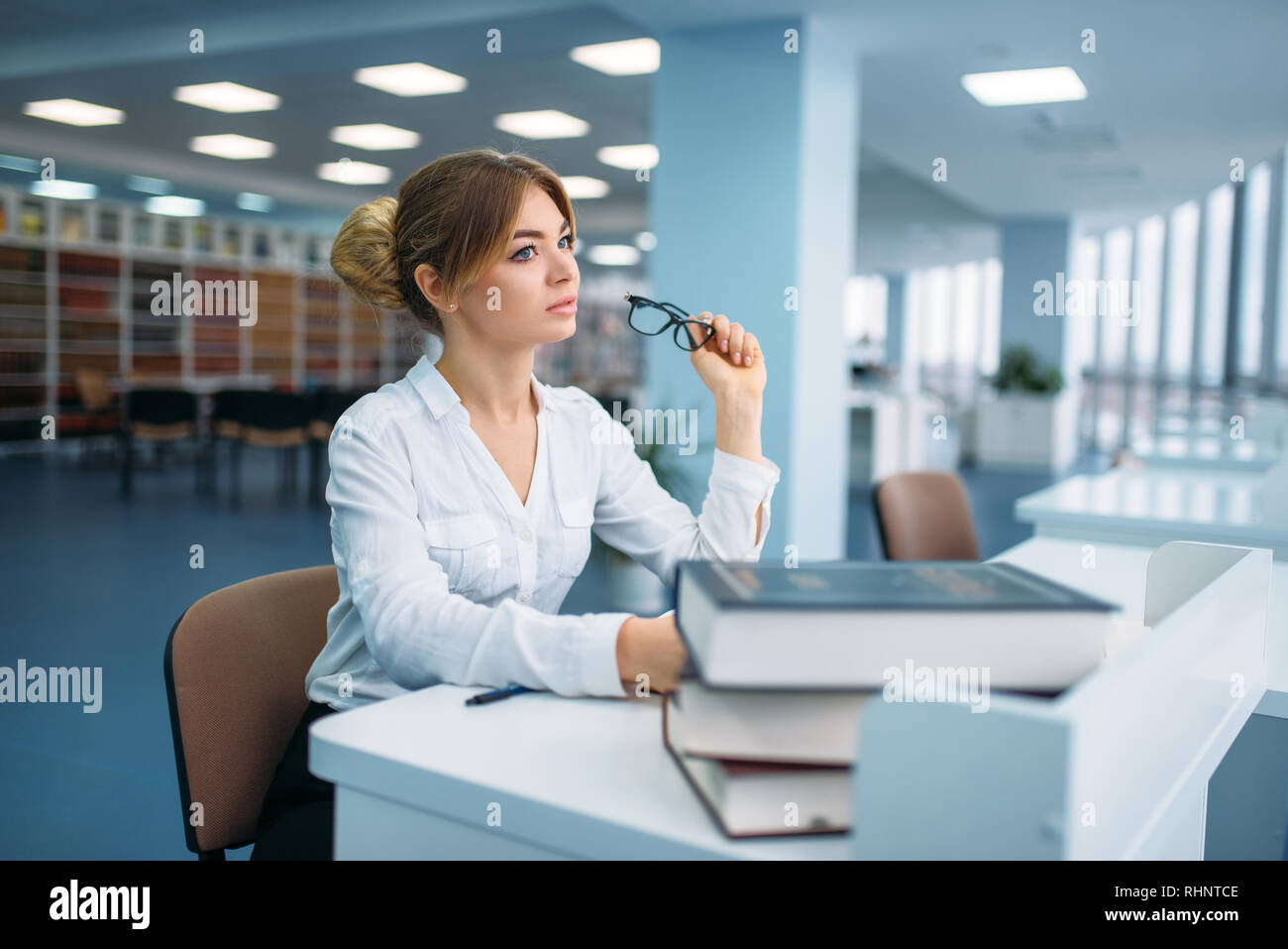 Pretty woman in glasses learning book in library. Female person in ...