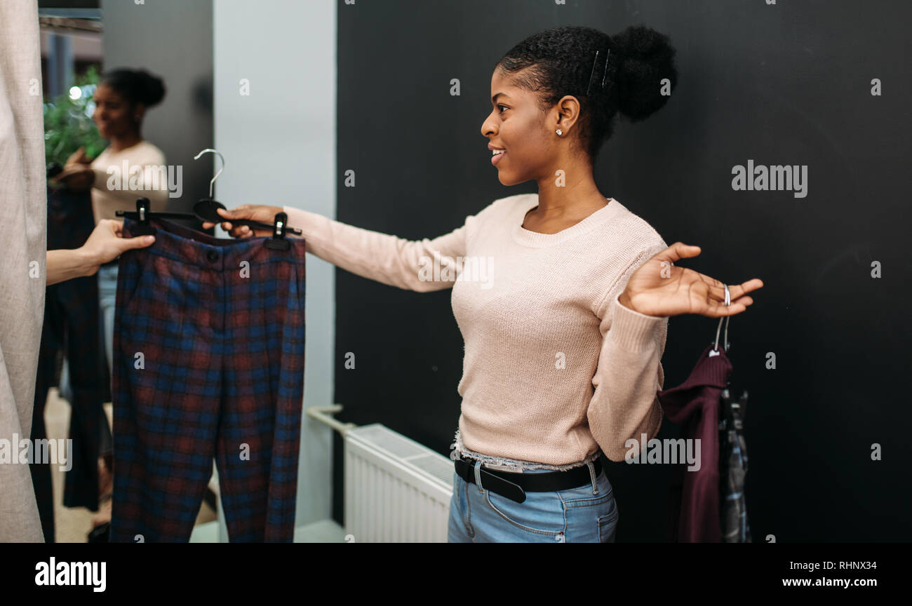 Two girlfriends choosing clothes in the dressing room, shopping ...