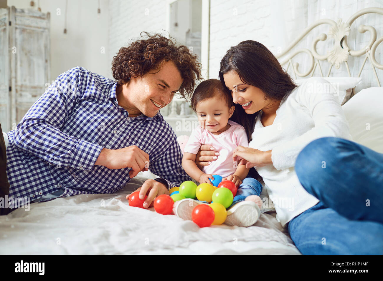 Happy family playing with the baby in the room. Young mother and father ...