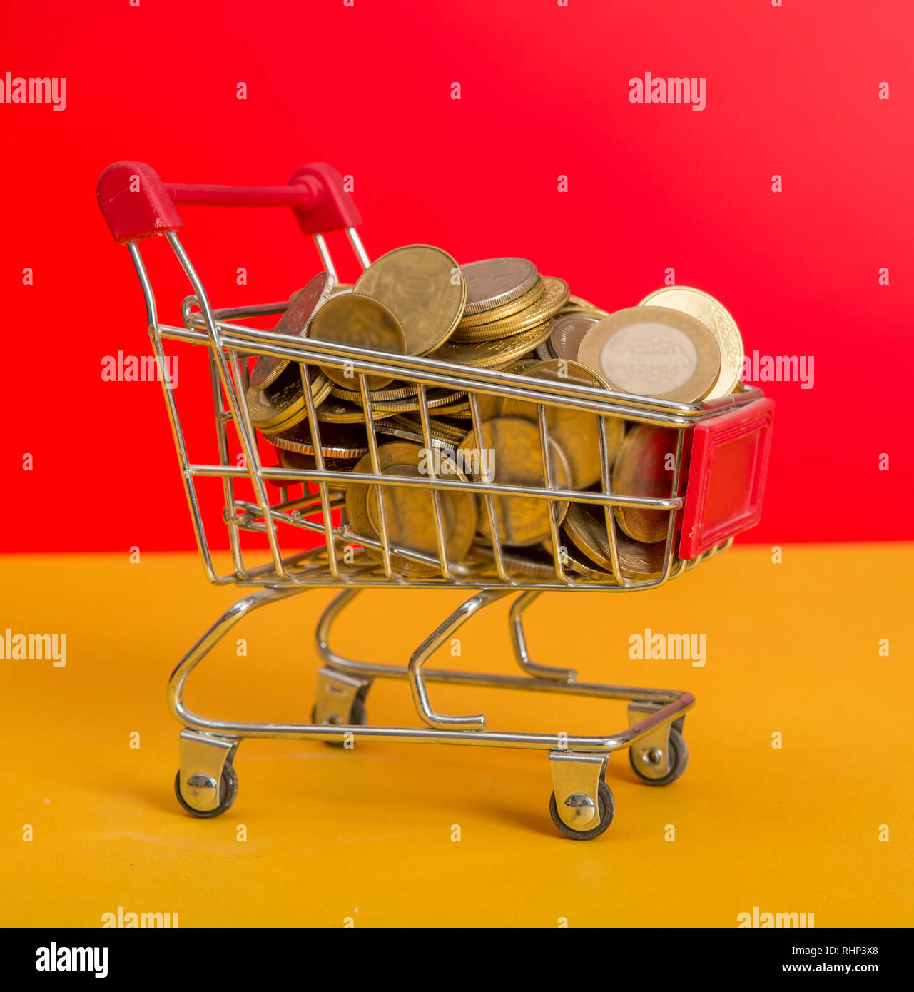 Coins loaded on shopping cart market theme Stock Photo - Alamy