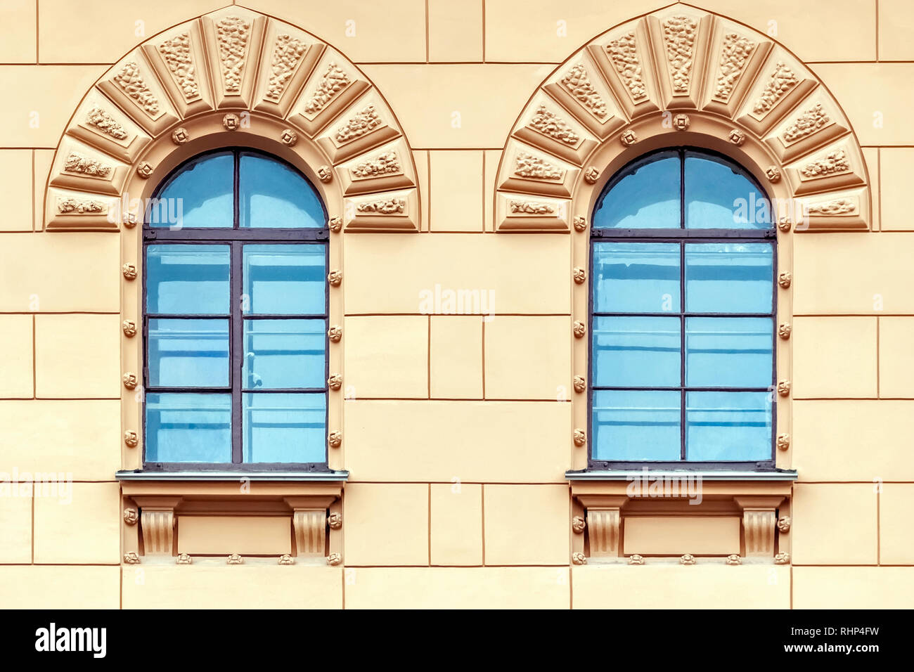Two arched window with dark brown frame on the background of beige wall ...