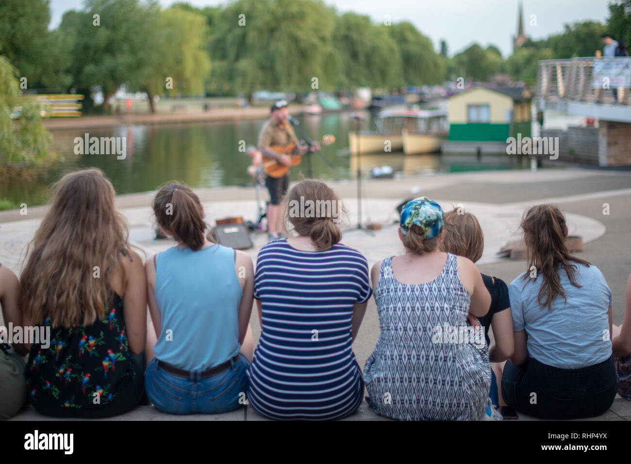 group of girls watching live performer in concert at river festival ...