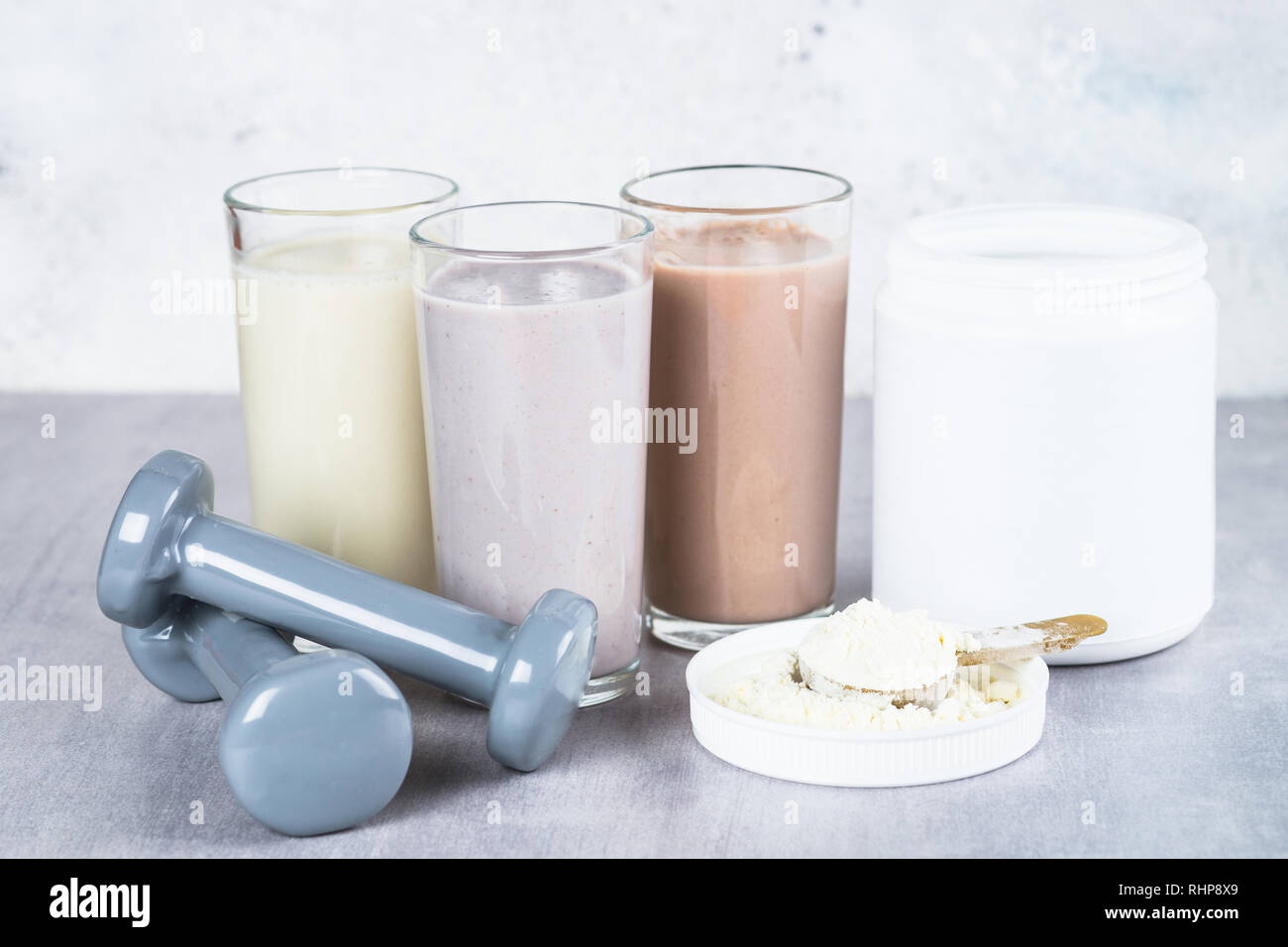 Protein cocktails, protein powder and dumbbell. Vanilla, berry and ...