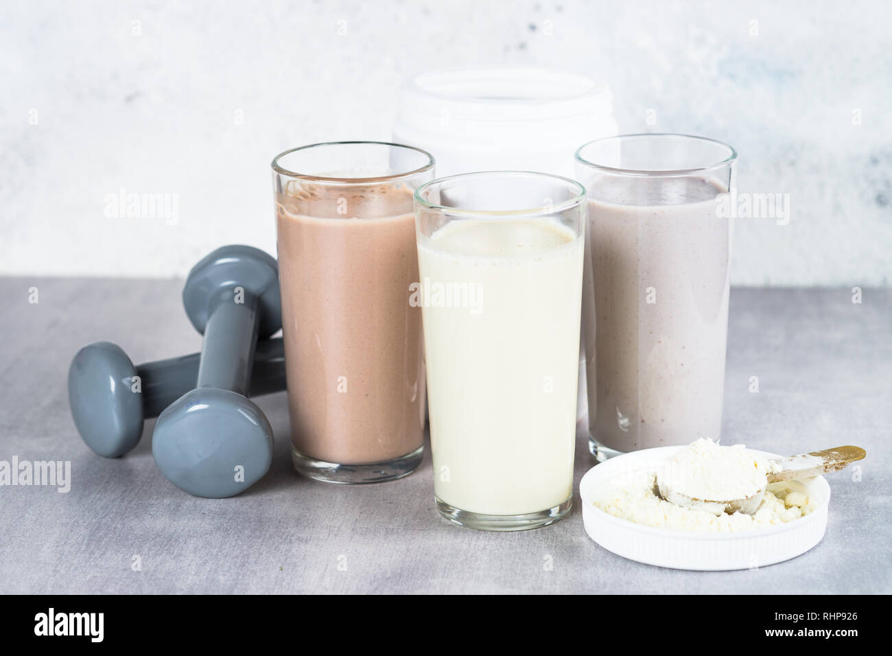 Protein cocktails, protein powder and dumbbell. Vanilla, berry and ...