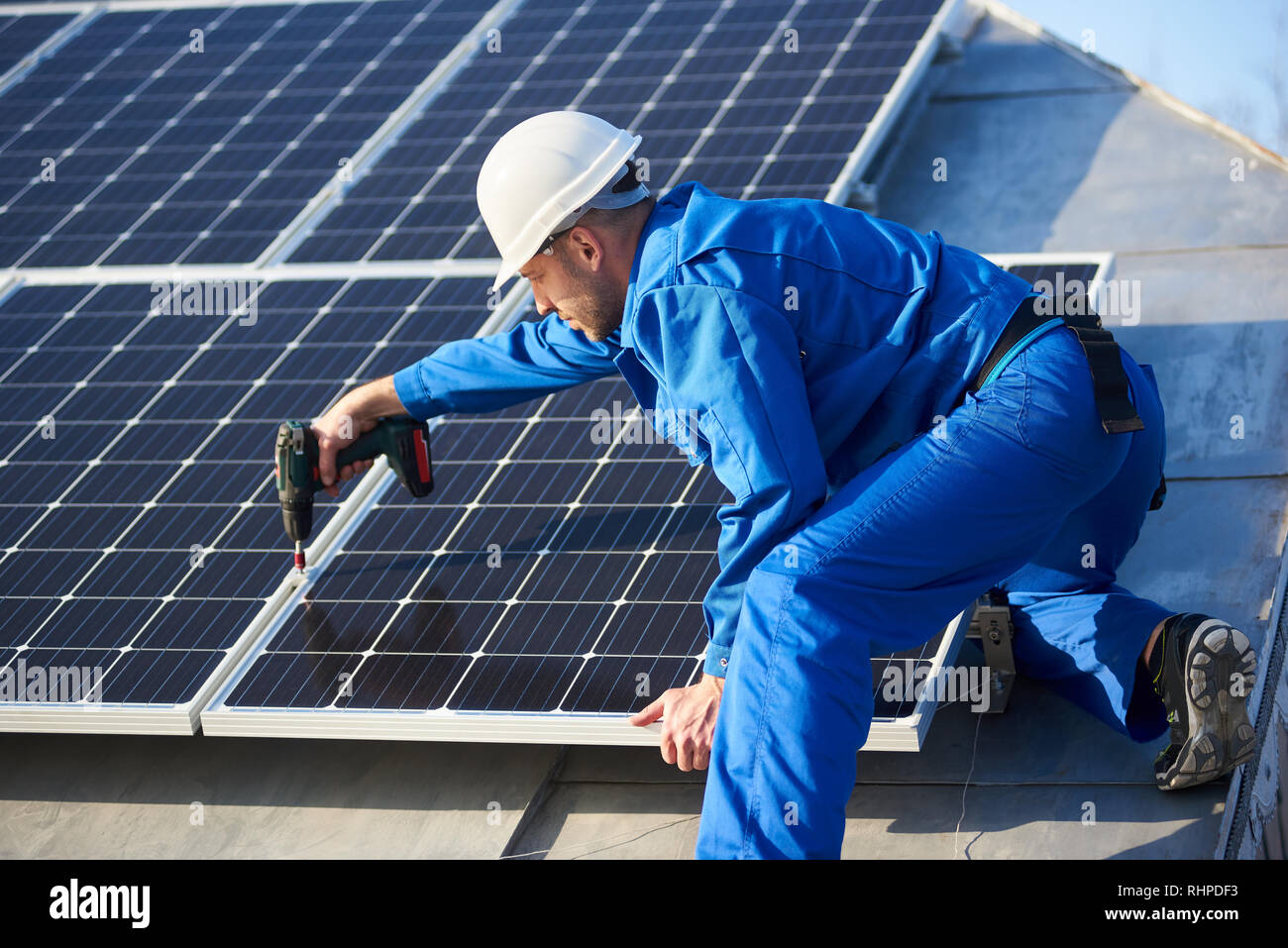 Male worker in blue suit and protective helmet installing solar ...