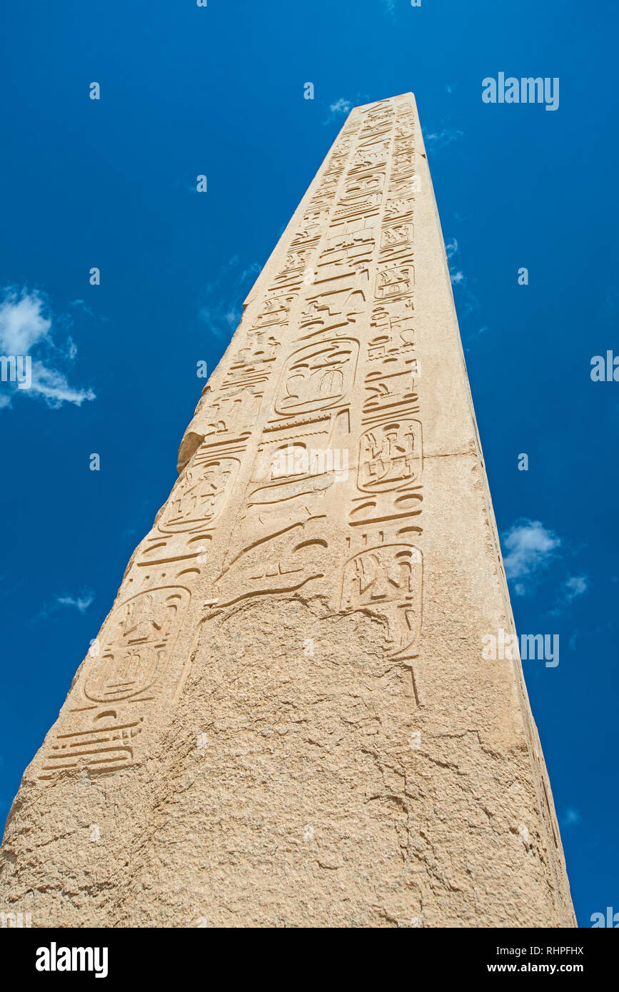 Large tall ancient egyptian obelisk at the temple of Karnak in Luxor with hieroglyphic carvings ...