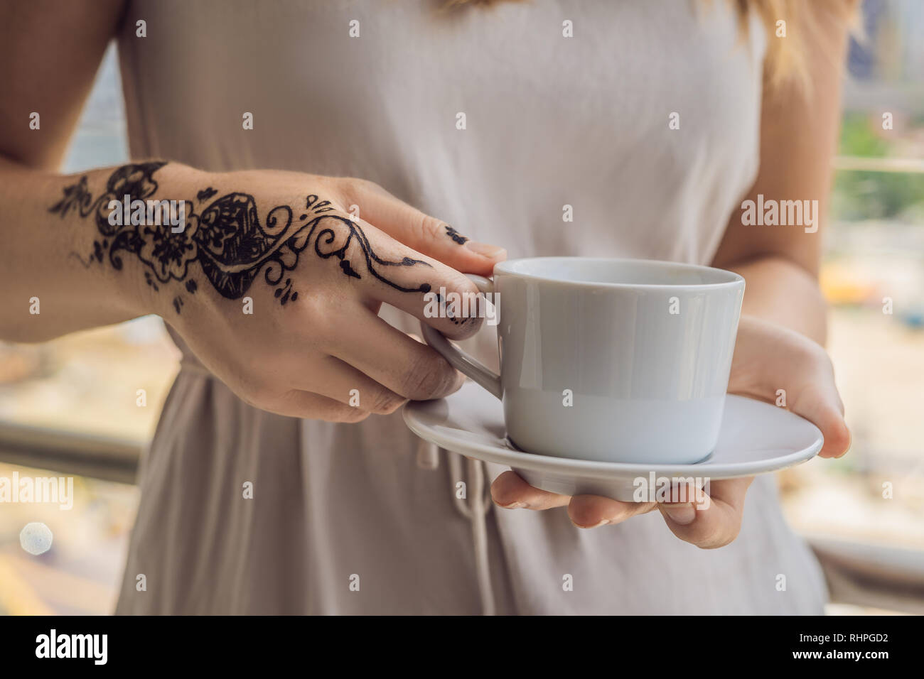 Young woman with a picture on the hand of henna - mehendi drinks coffee ...