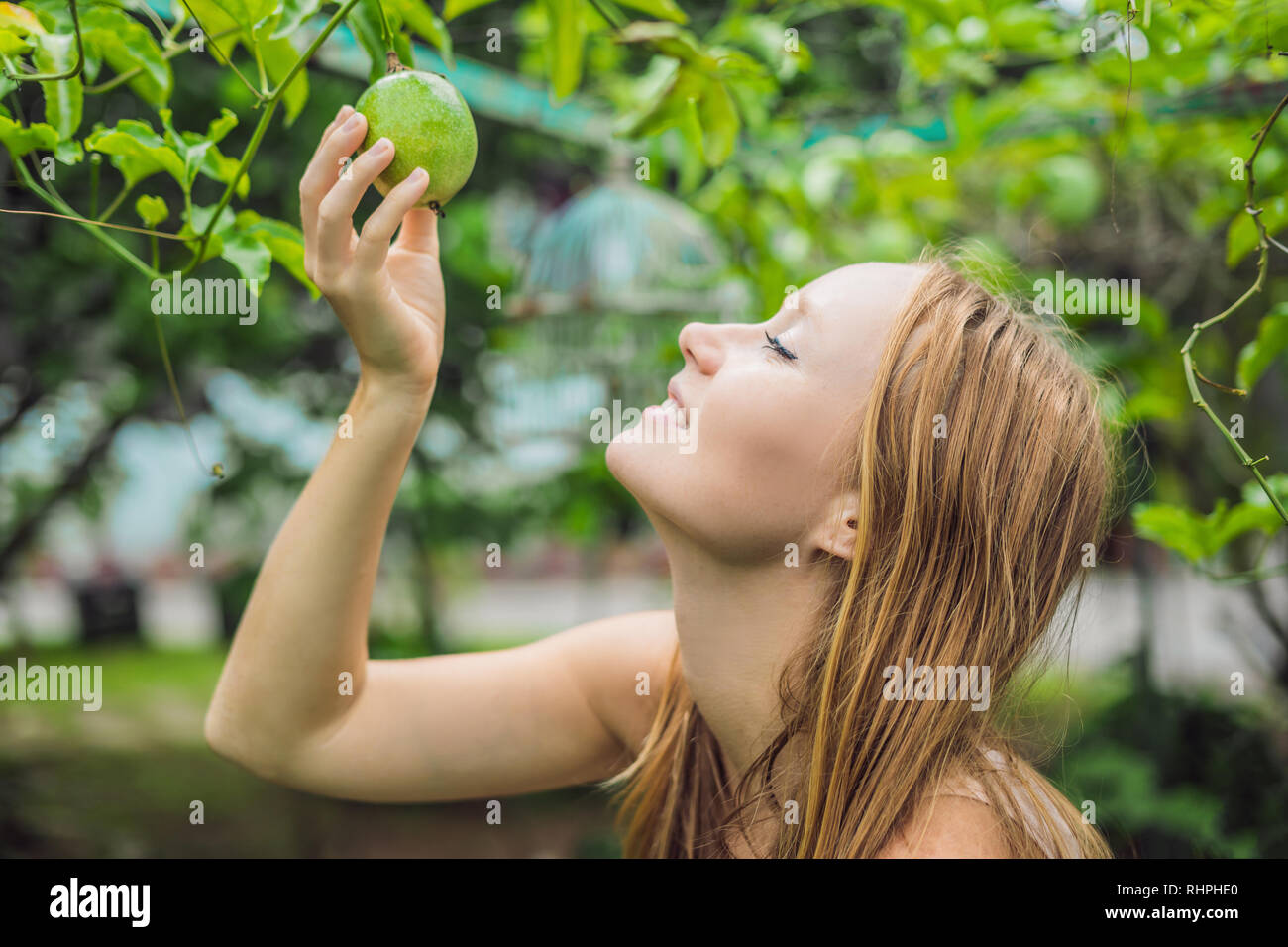 Young woman smelling the passion fruit in the garden Stock Photo - Alamy