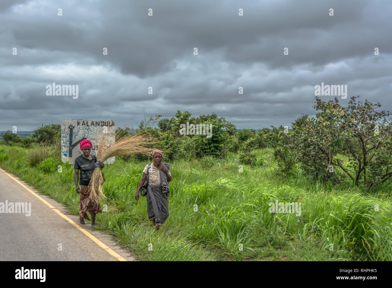 Malange / Angola - 12 08 2018: View of two old women loading farm tools ...