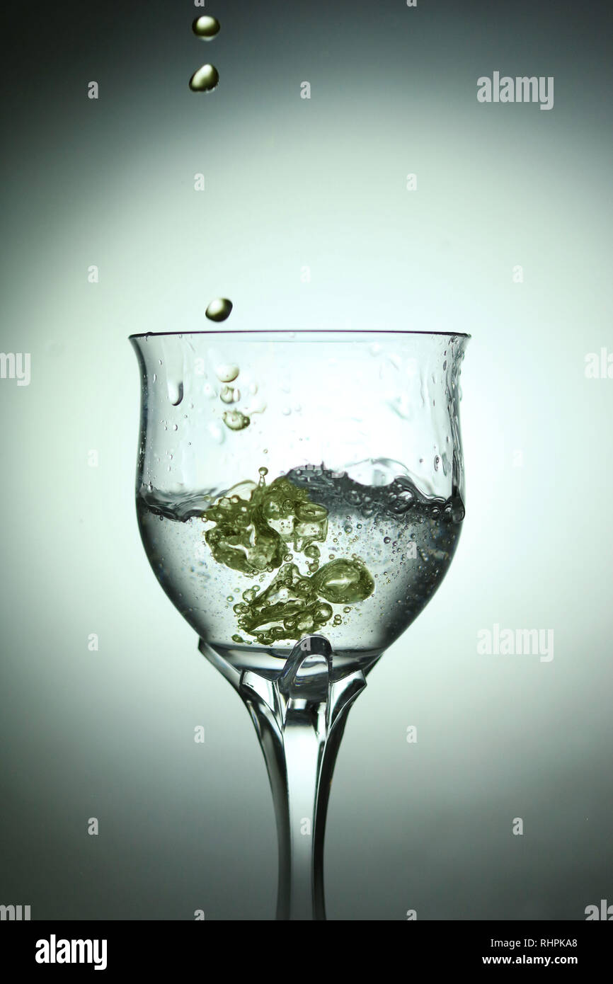 Oil splashing into a glass of water Stock Photo - Alamy