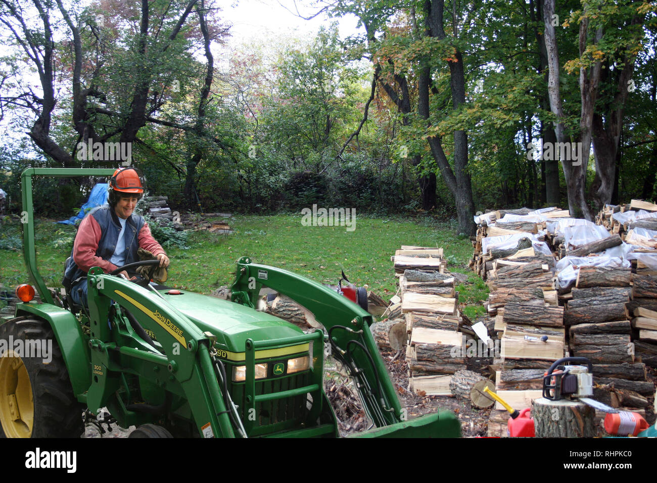Lady driving tractor by wood pile Stock Photo - Alamy