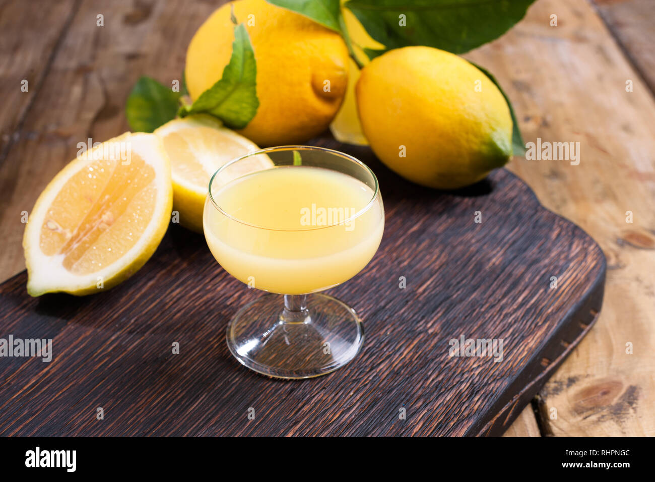 limoncello in a glass and fresh citrus fruits with green leaves ...