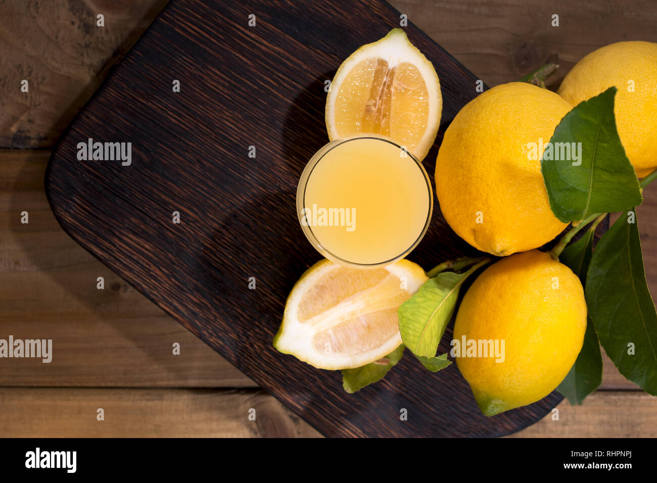 limoncello in a glass and fresh citrus fruits with green leaves ...