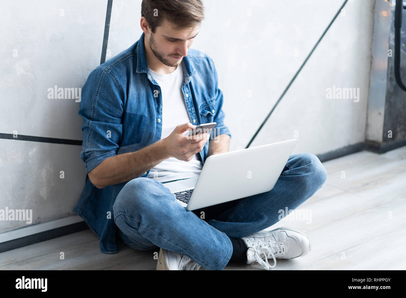 Young caucasian man sitting over gray wall using computer laptop and ...