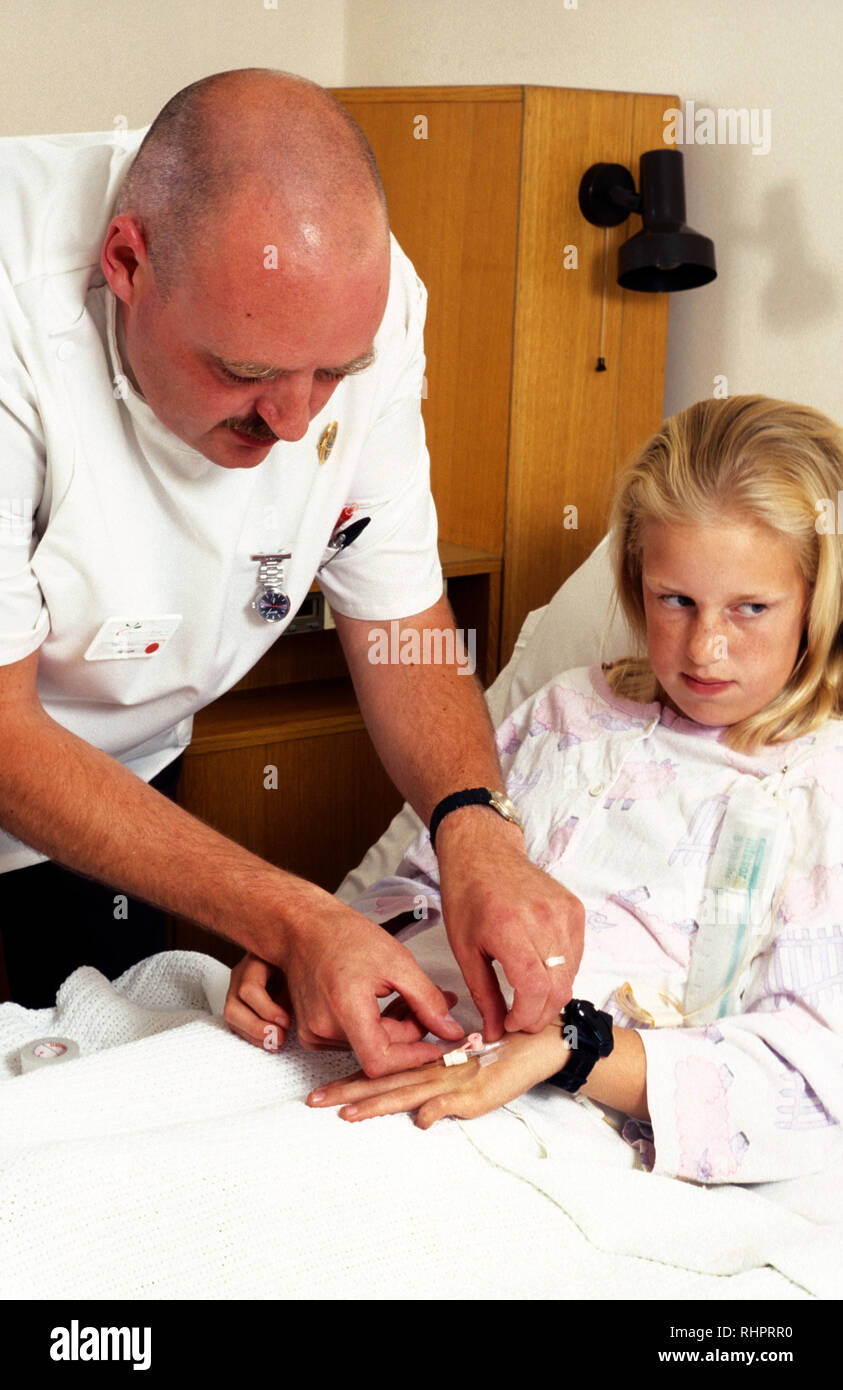 nurse or doctor inserting cannula for intravenous fluids into young ...