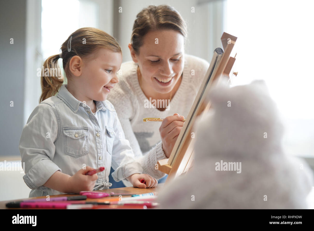 Mother teaching young daughter to draw on easel at home Stock Photo - Alamy