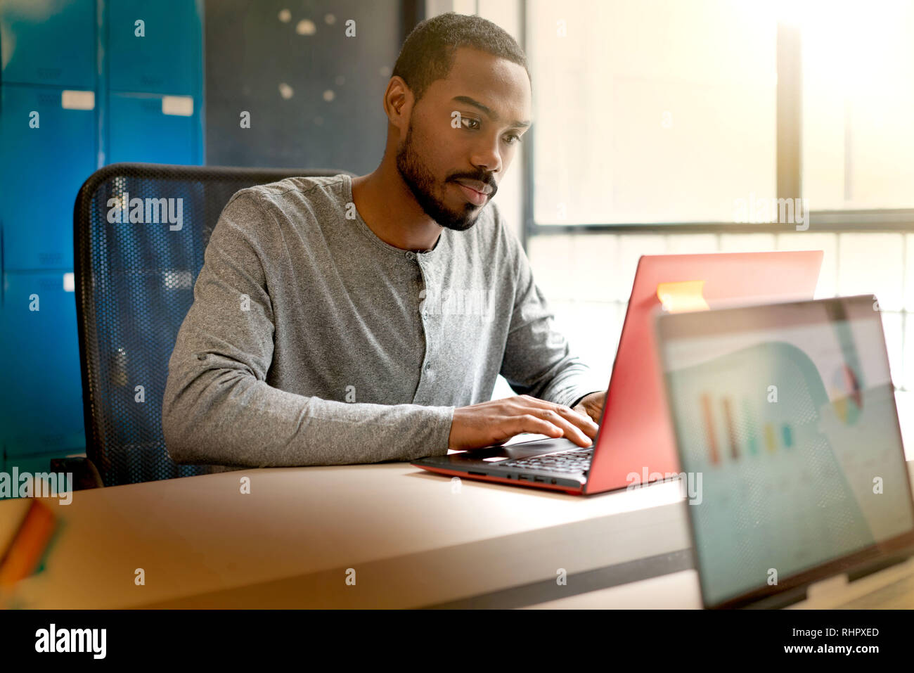 Attractive young black man working in modern office space Stock Photo ...