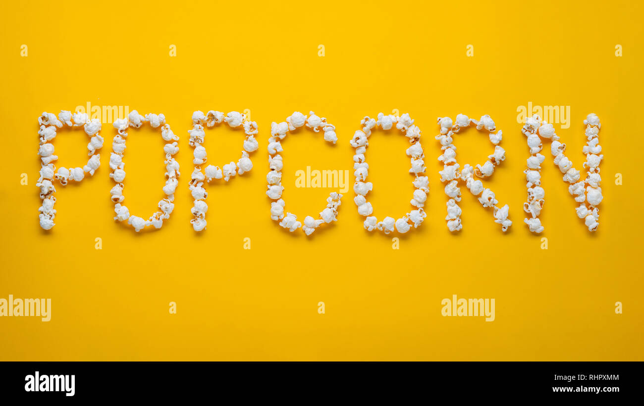 The word POPKORN is laid out from pieces of salt popcorn on a yellow ...
