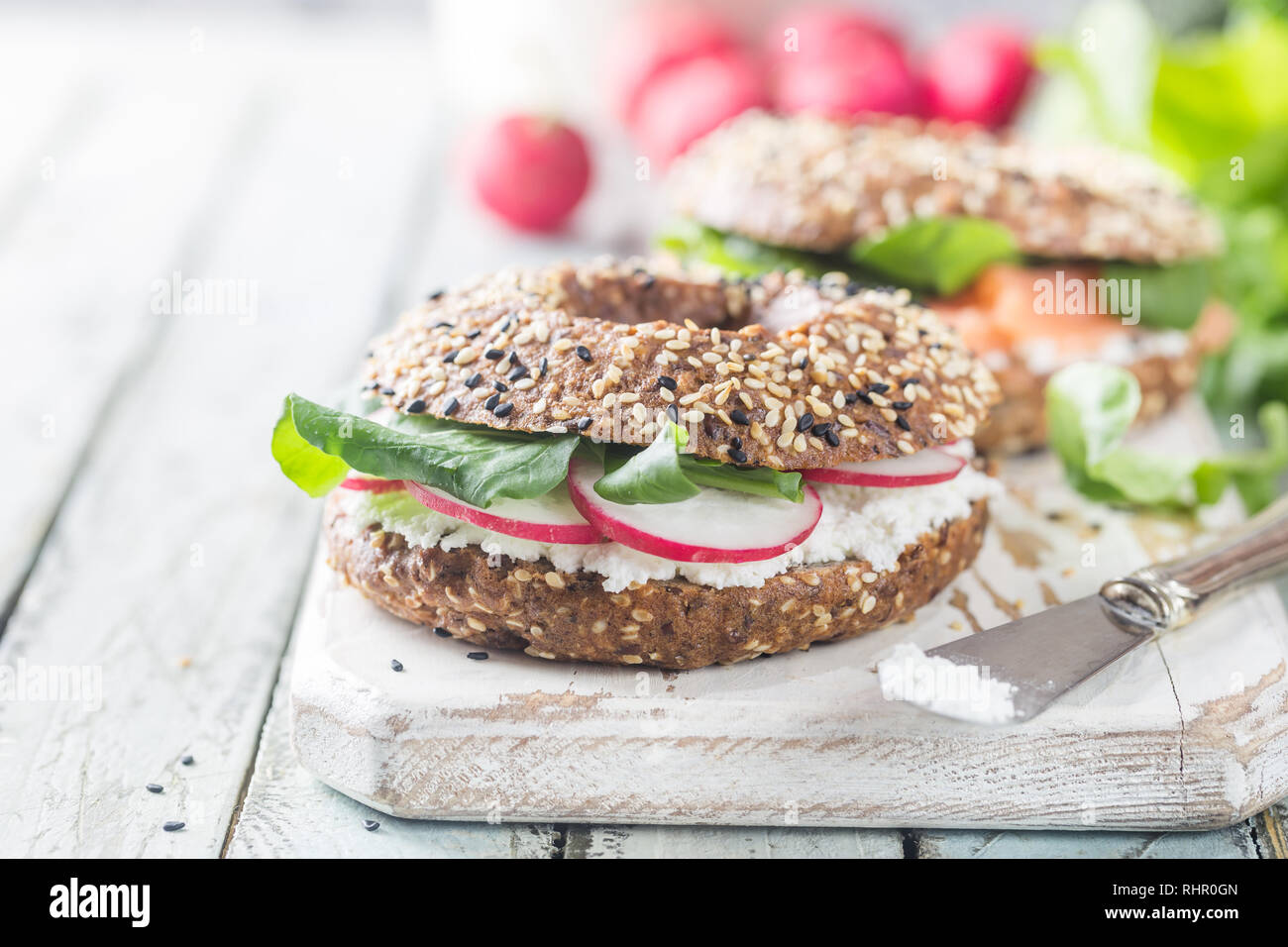 Bagels with cream cheese avocado, fish, arugula and radish on old ...