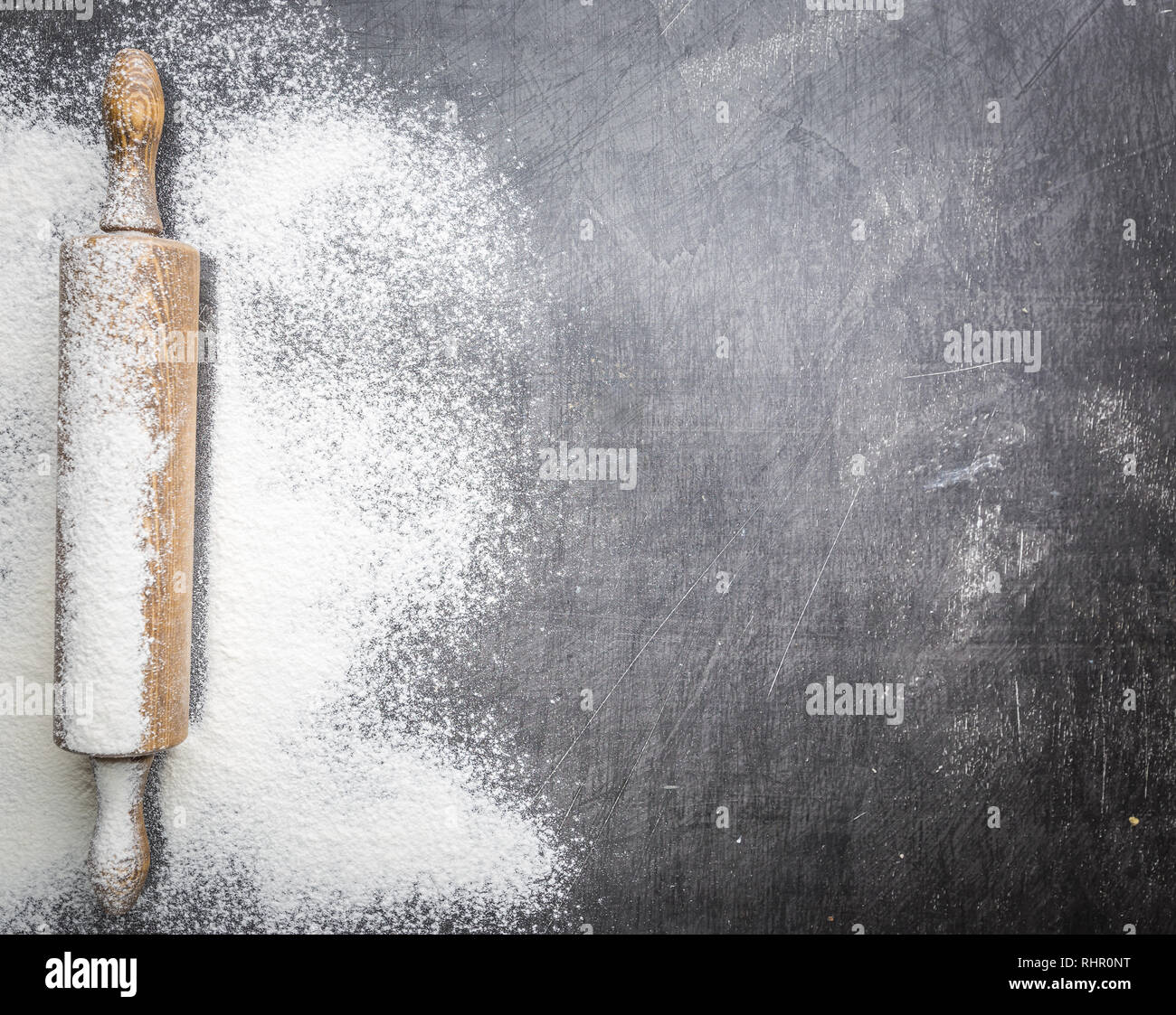 Rolling pin and white flour on a dark background. Free space for text ...
