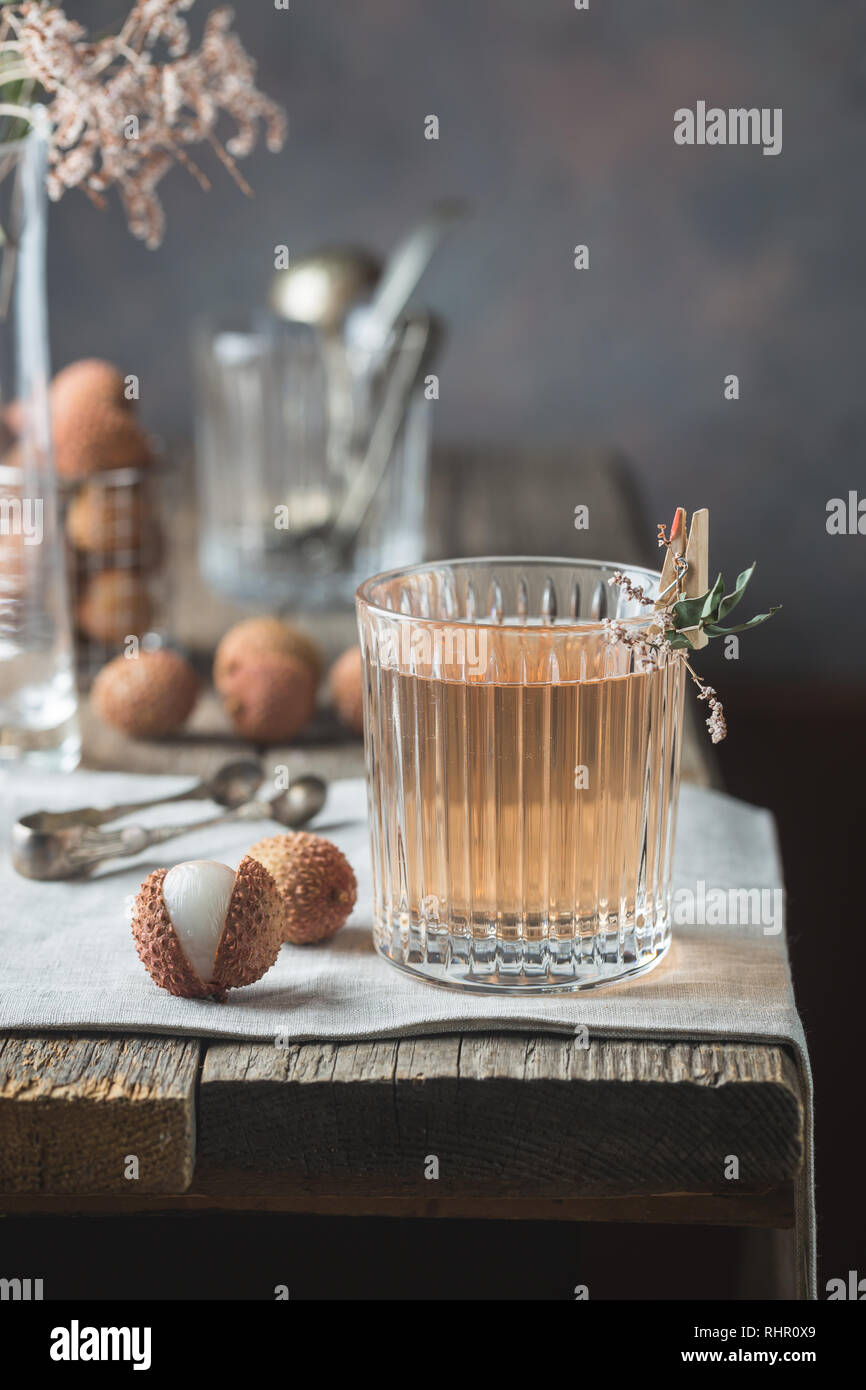 Glass of cold lychee cocktail on the old wooden table, rustic style ...