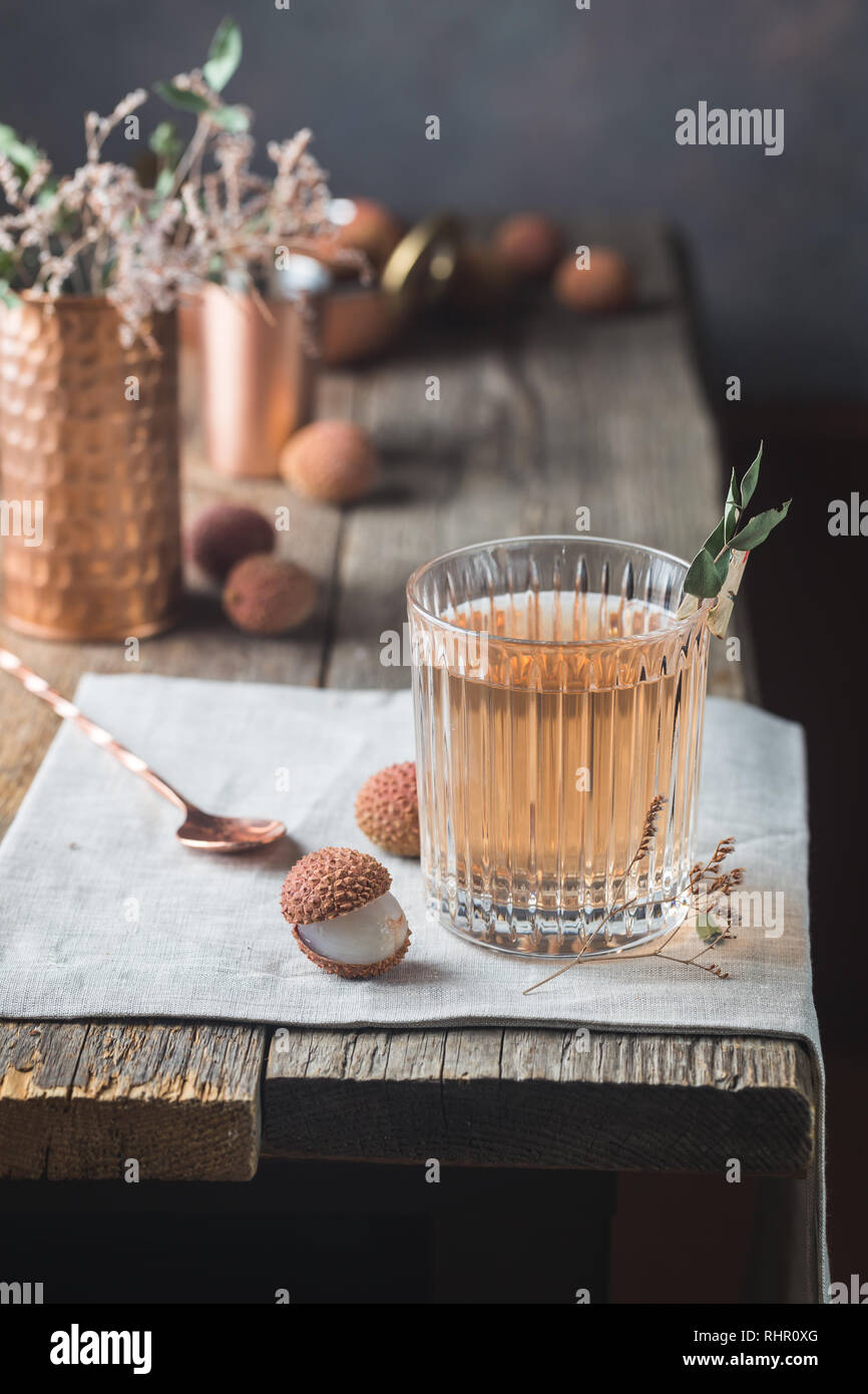 Glass of cold lychee cocktail on the old wooden table, rustic style ...