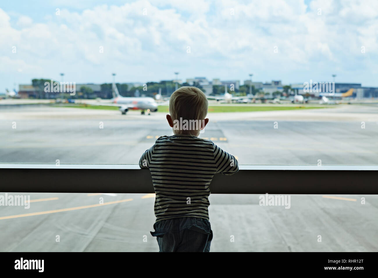 Little baby boy waiting boarding to flight in airport transit hall and ...