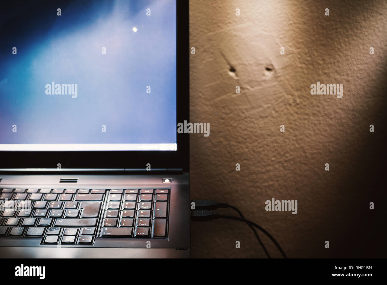 Dirty old laptop in front of an old wall interestingly illuminated ...