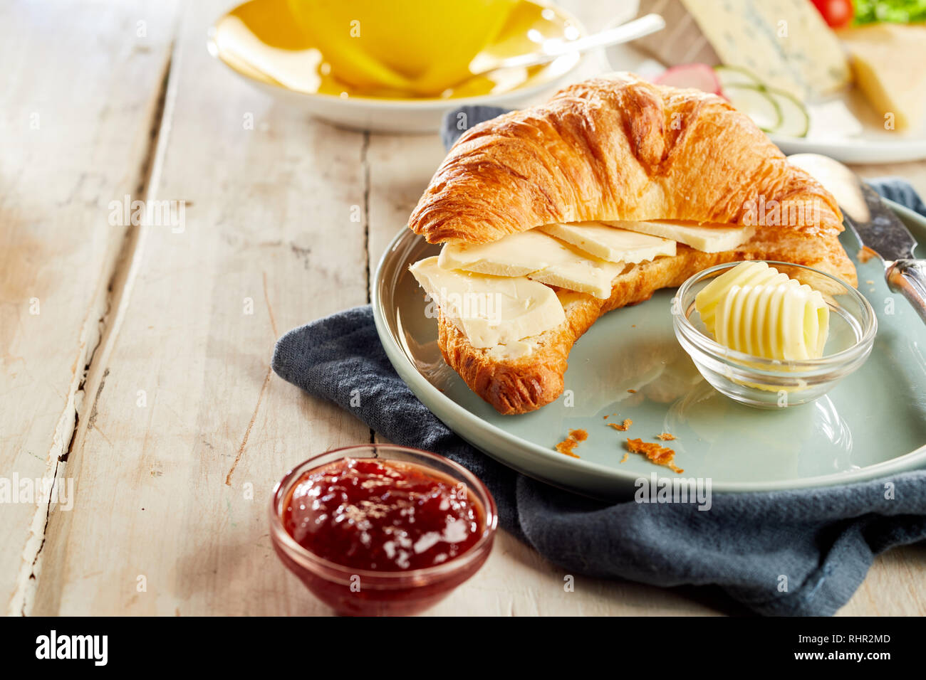 Croissant sliced in half, served with cheese, butter and ketchup in ...