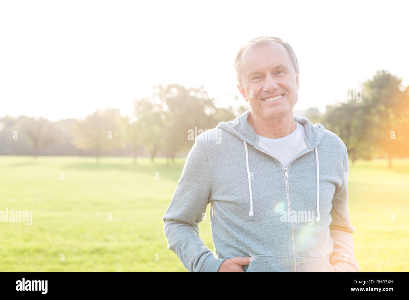Healthy senior man in hooded jacket smiling at park Stock Photo - Alamy