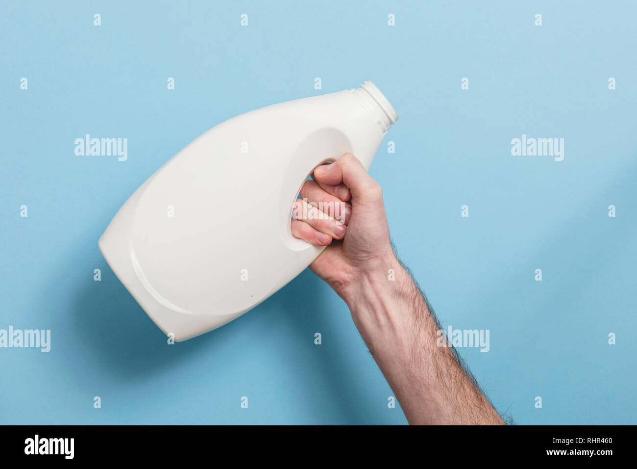 Hand holding empty plastic bottle recycling against a blue background ...