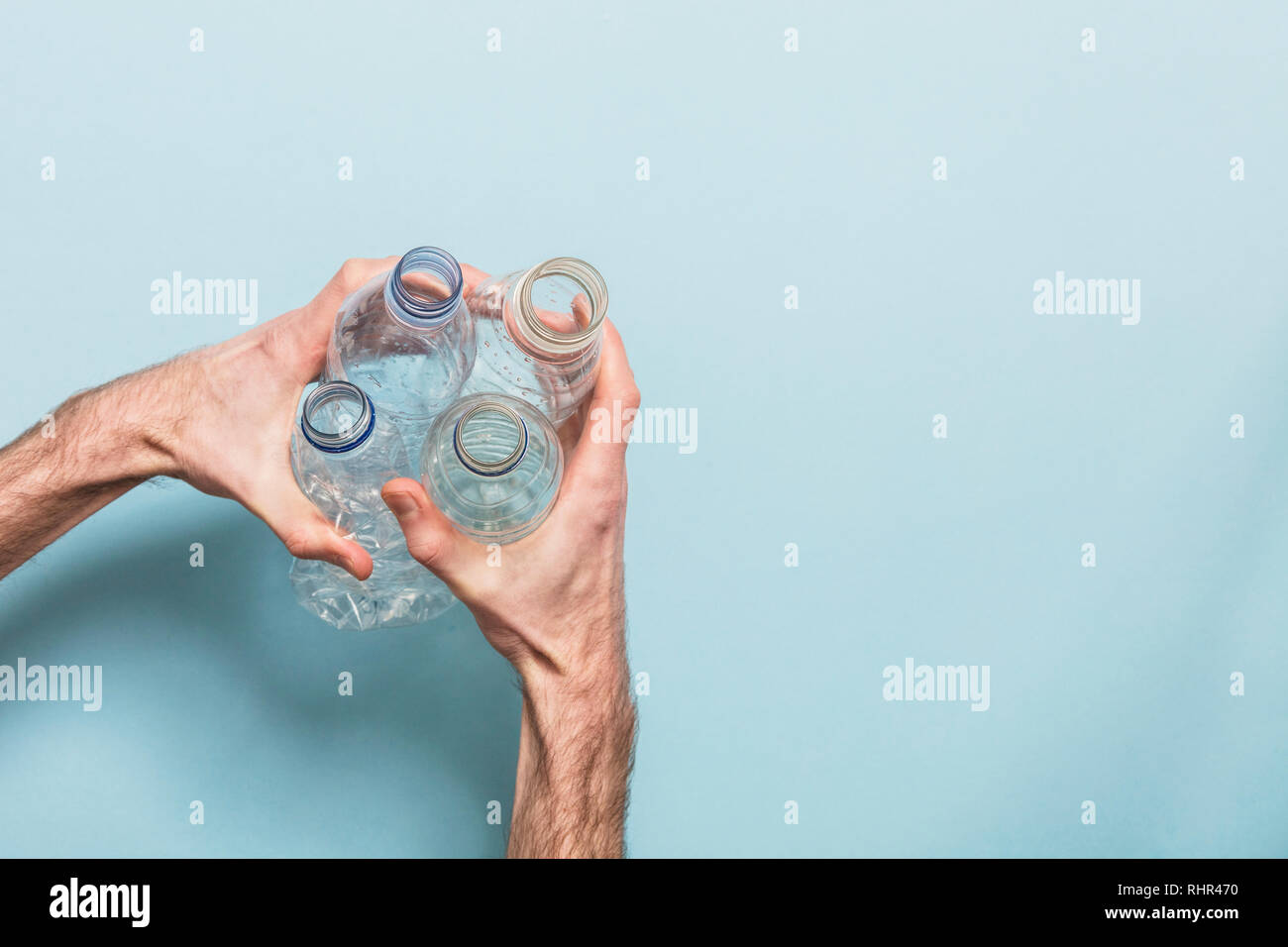 Hand holding empty plastic bottle recycling against a blue background ...