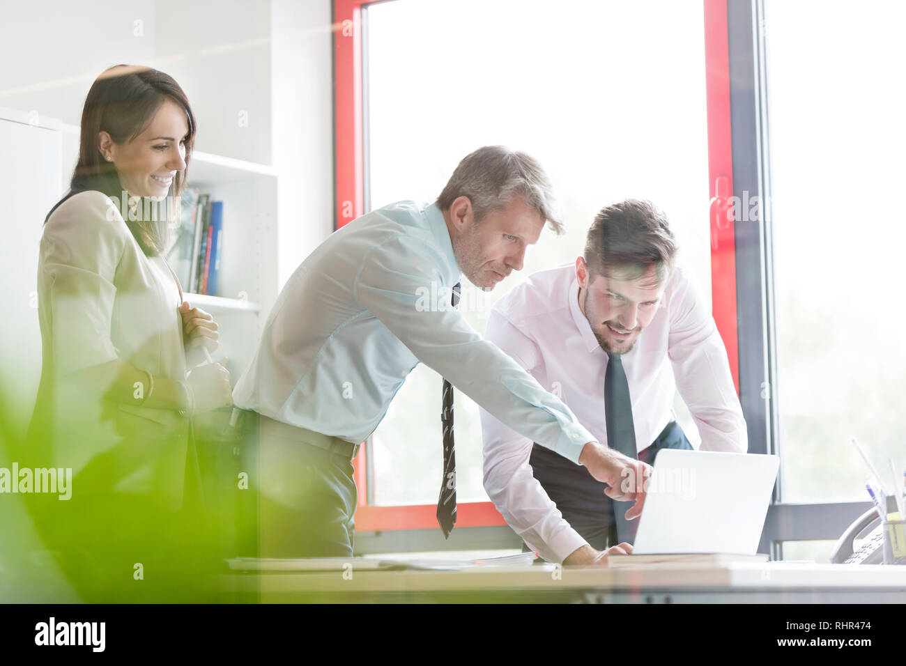 Manager explaining employees over laptop at desk in office Stock Photo ...
