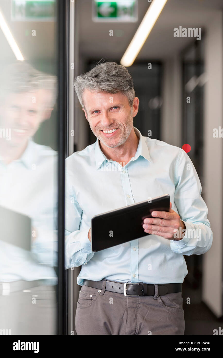 Portrait of smiling businessman holding digital tablet in office Stock ...
