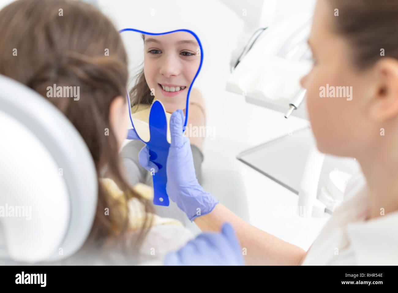 Dentist showing mirror to smiling girl patient at dental clinic Stock ...