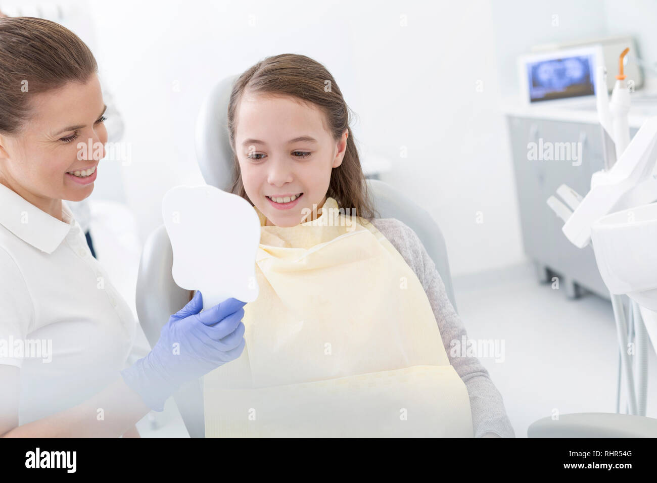 Female dentist showing mirror to smiling patient at clinic Stock Photo ...