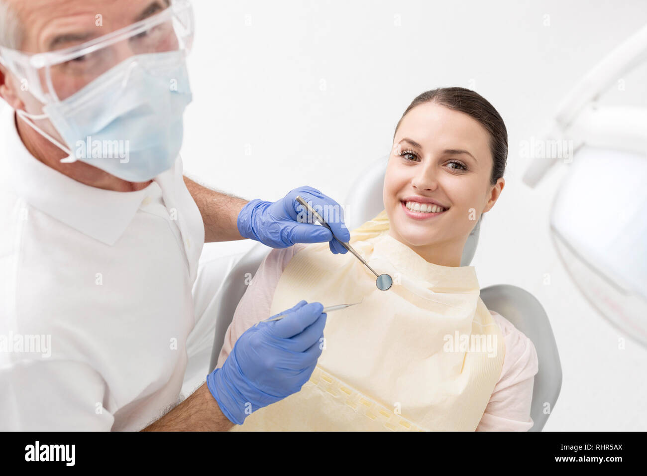 High angle portrait of dentist and smiling patient with equipment at ...