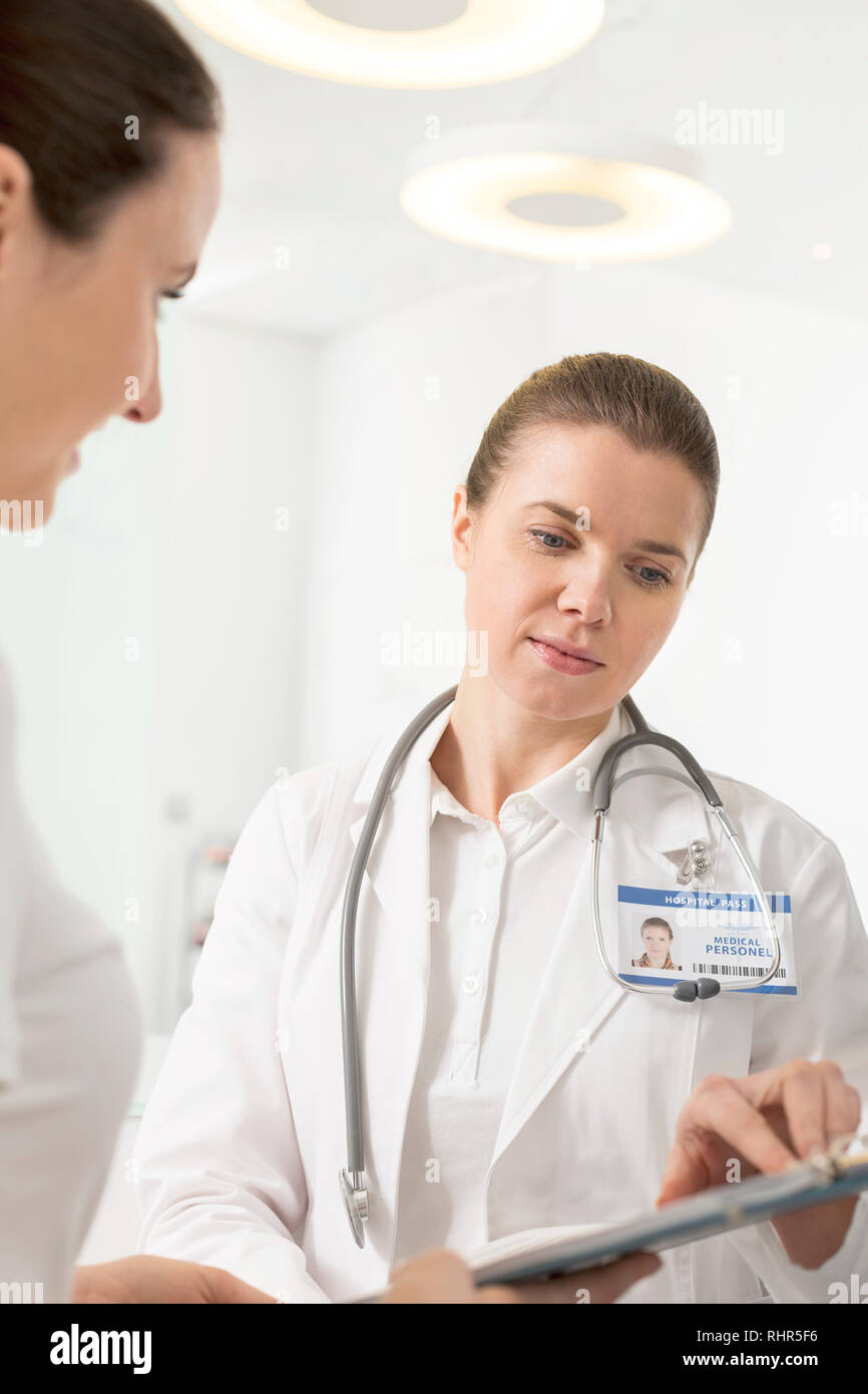 Female doctor discussing with assistant over clipboard at hospital ...