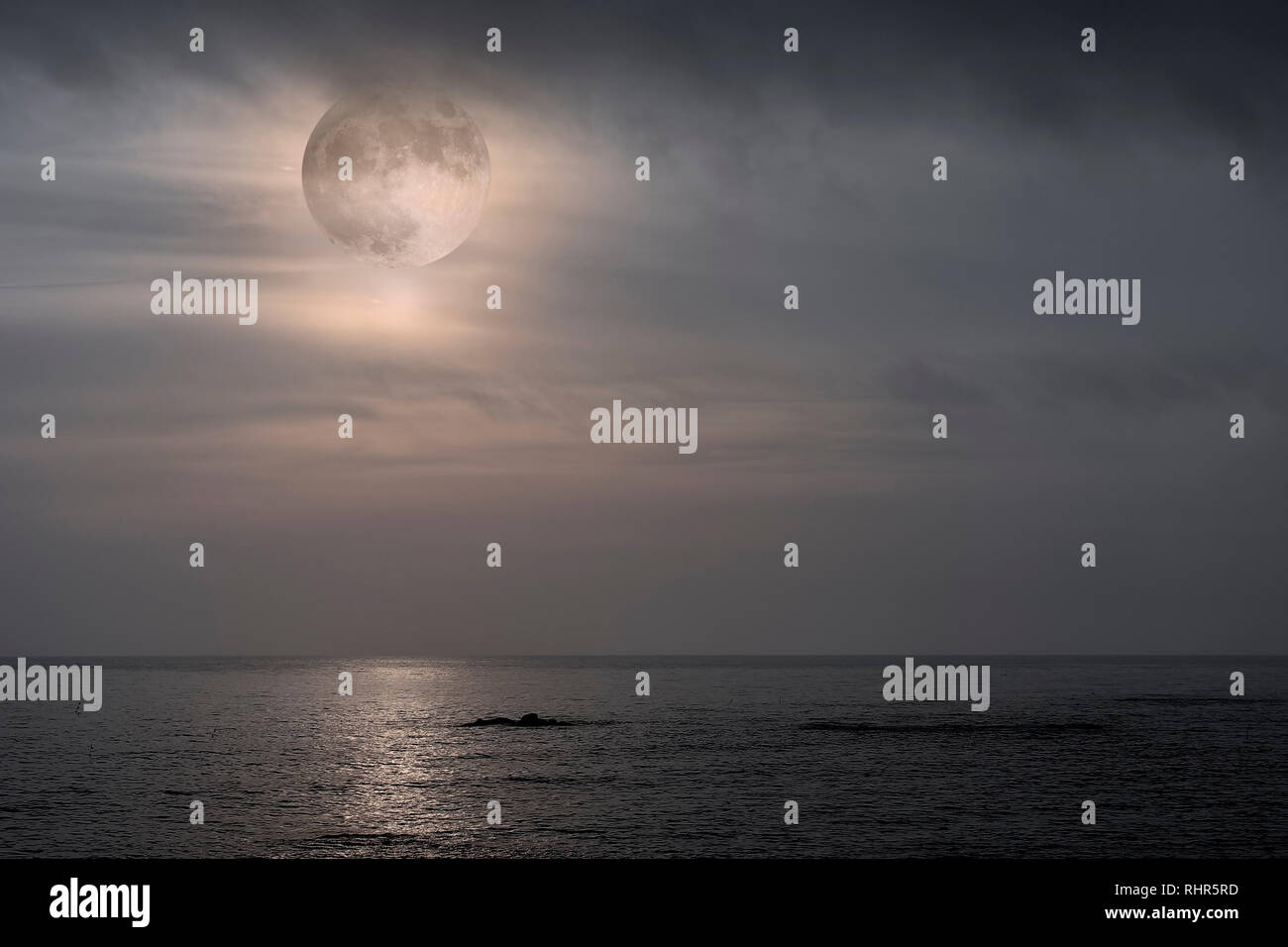 Rising full moon in the sea at dusk Stock Photo - Alamy